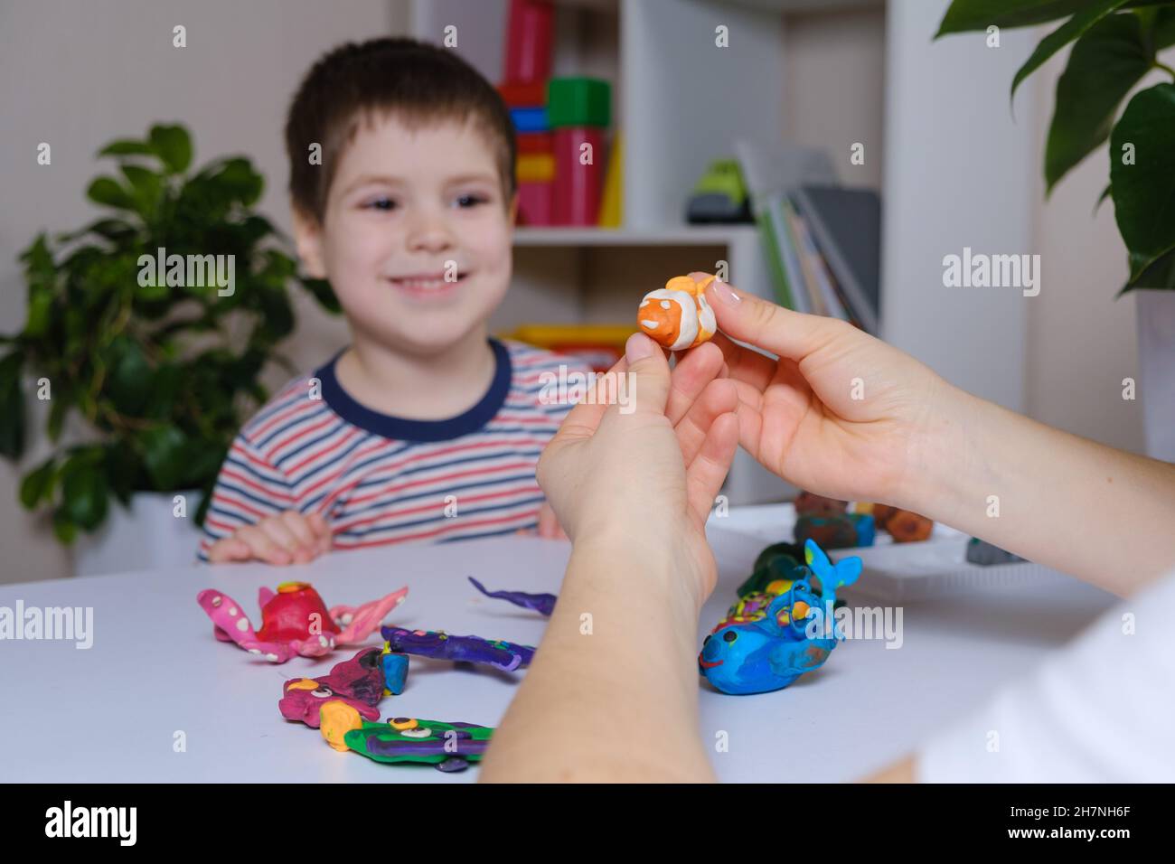Mother and son sculpt from plasticine of marine animals, orange clown ...