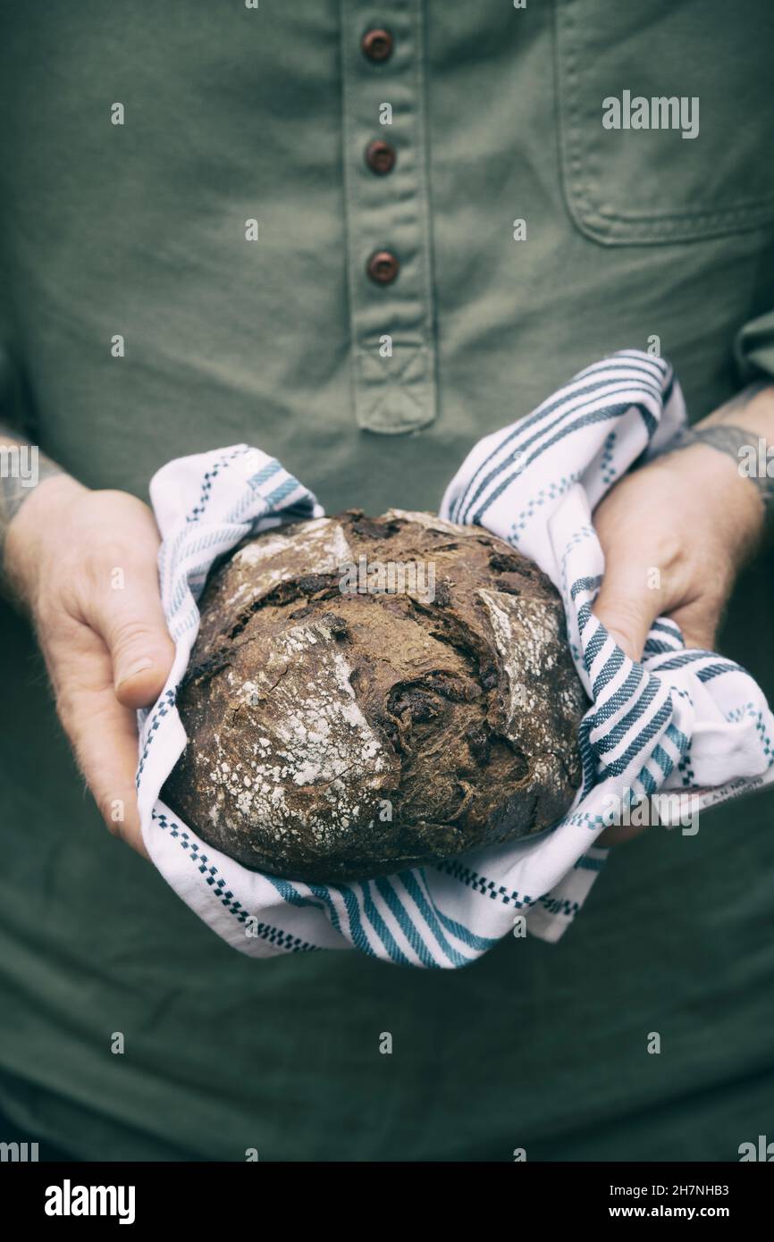 Man holding a loaf of chocolate sourdough bread Stock Photo - Alamy