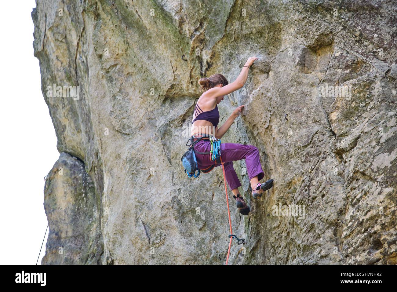 Strong female climber climbing steep wall of rocky mountain ...