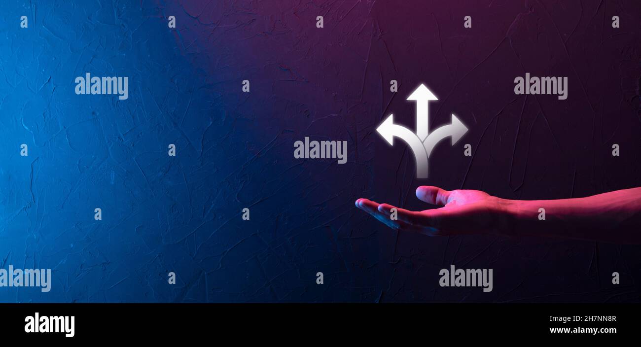 Businessman in a suit holds a sign showing three directions. in doubt ...