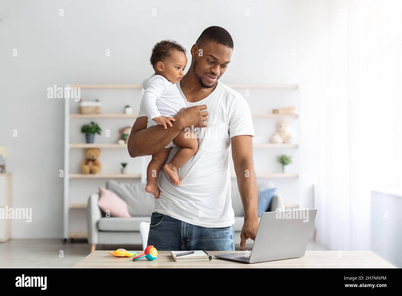 Black Man Holding Little Baby On Hands And Using Laptop At Home Stock ...