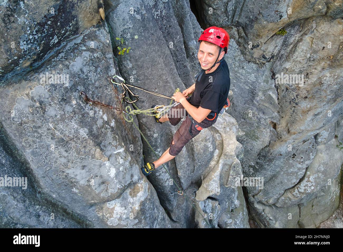 Strong male climber climbing steep wall of rocky mountain. Sportsman ...