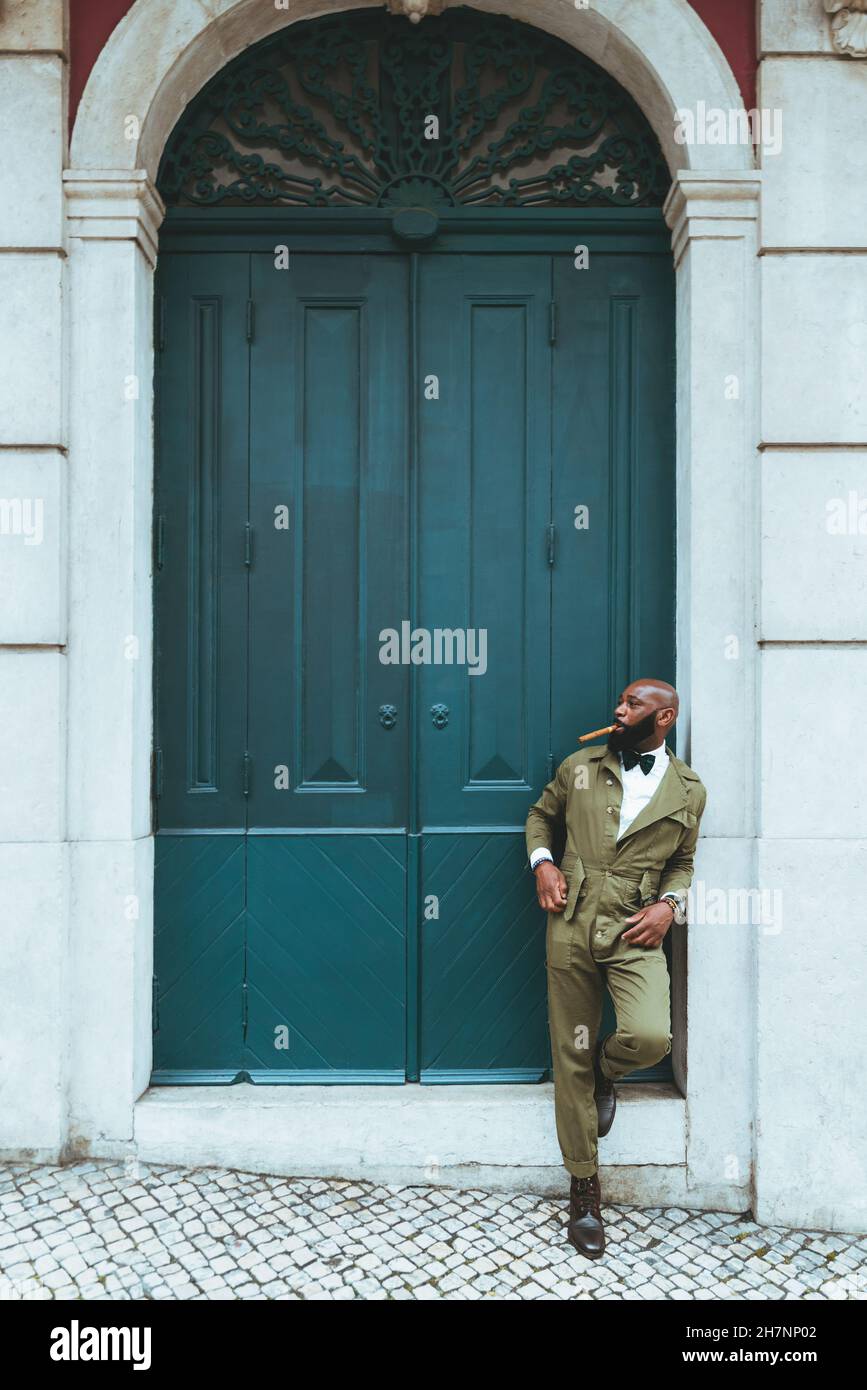 A handsome dapper adult bald bearded man with a cigar in his mouth and ...