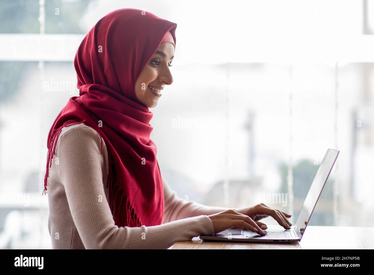 Young muslim woman typing on computer keyboard, cafe interior Stock ...