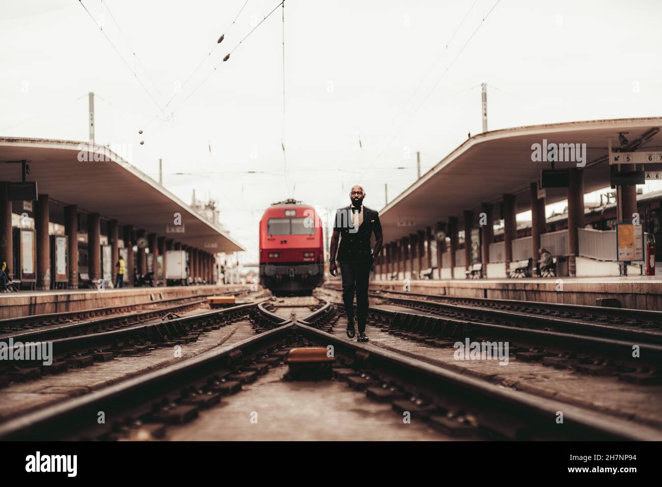 A dapper bald bearded African man in a fashionable suit with a bow-tie ...
