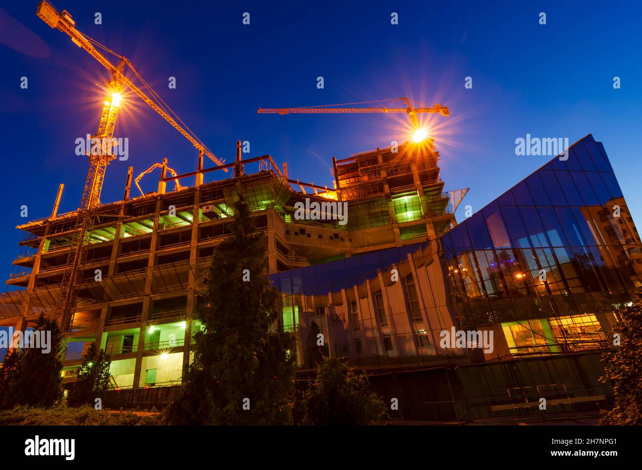 Building cranes and construction site at night. Colorful industrial ...