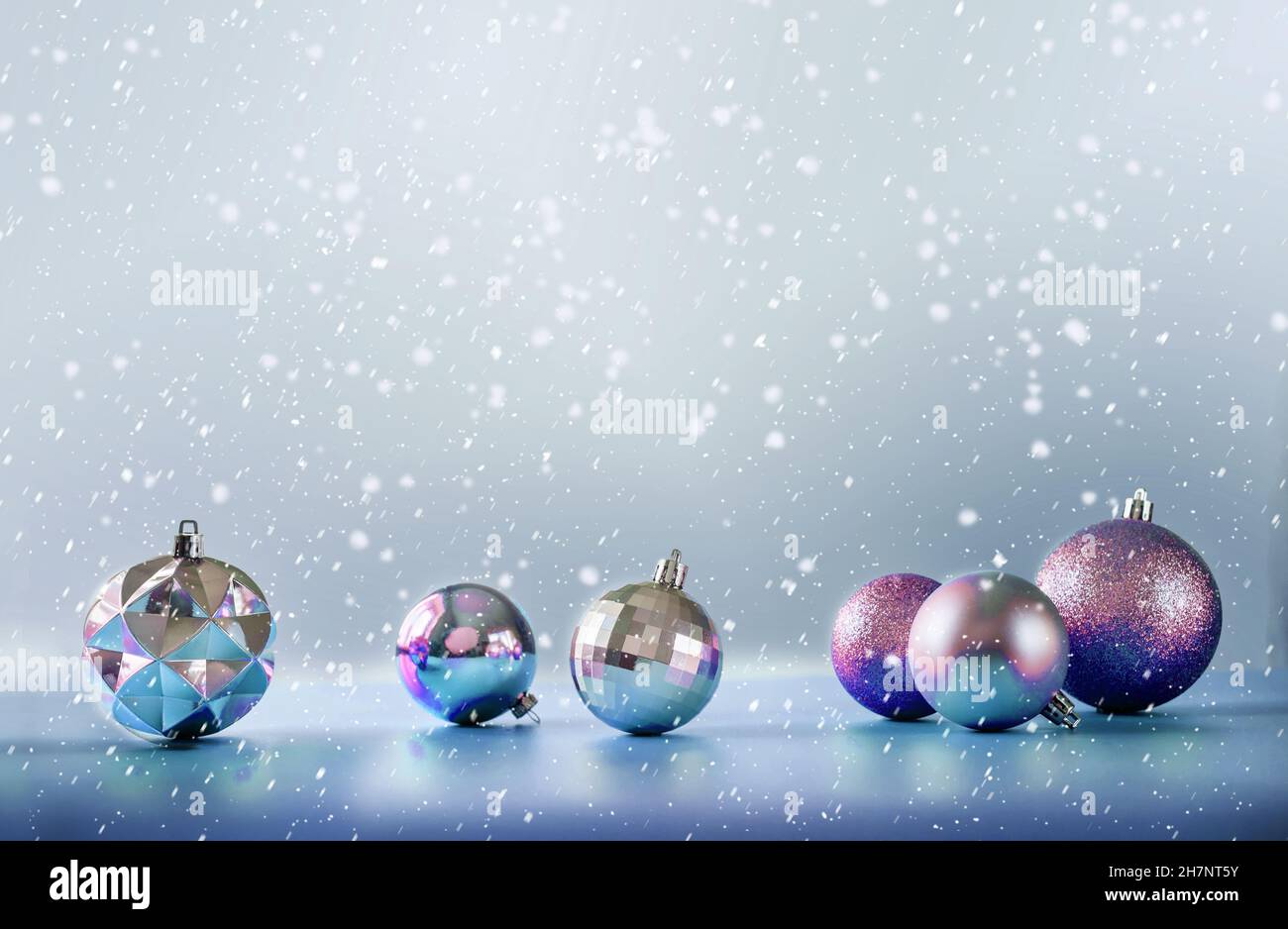 Purple and silver Christmas tree bulbs on blue background with falling ...