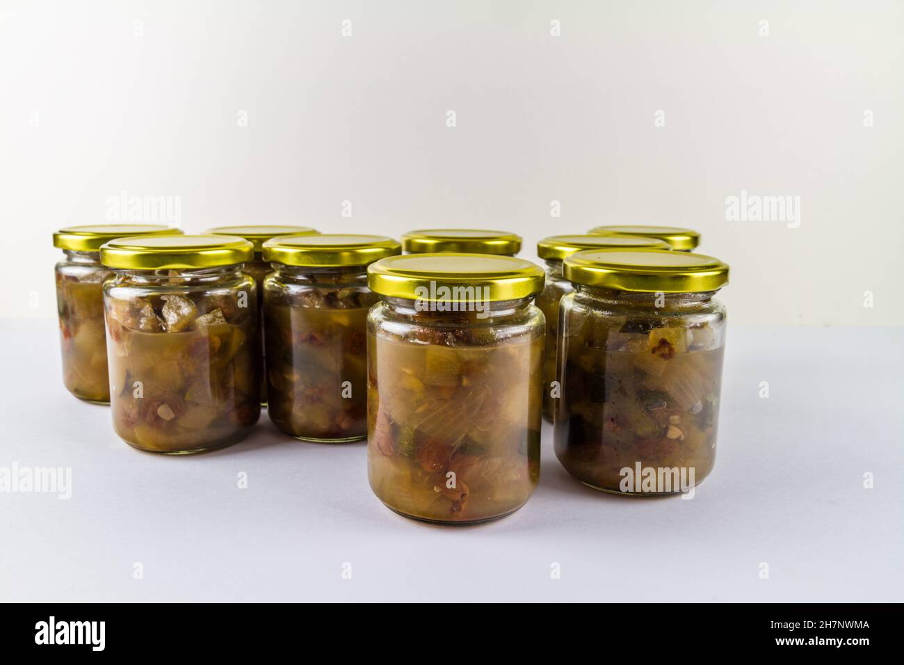Chutney after courgette grew into marrow. Several jars white background ...
