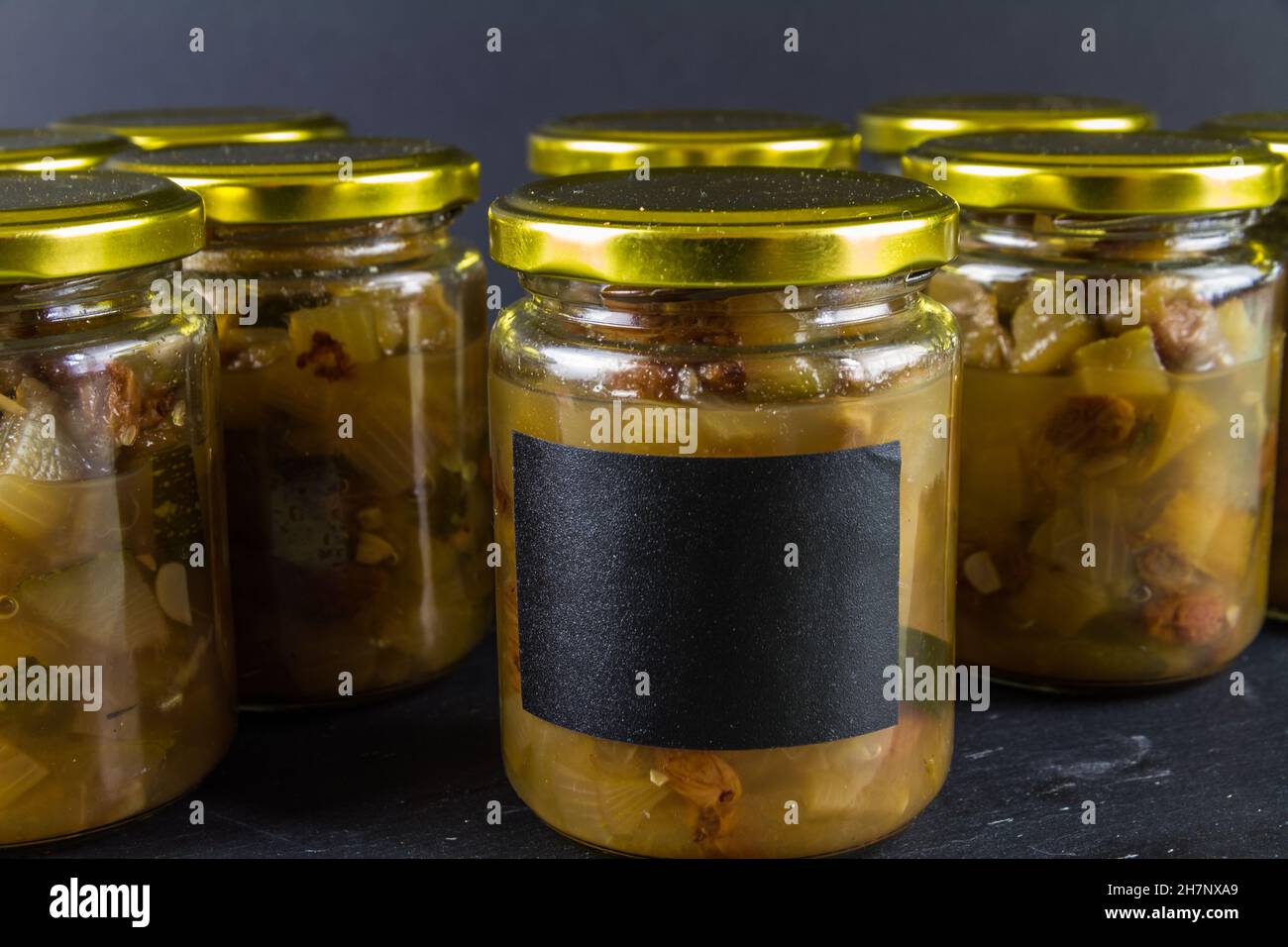 Chutney after courgette grew into marrow. Several jars black background ...