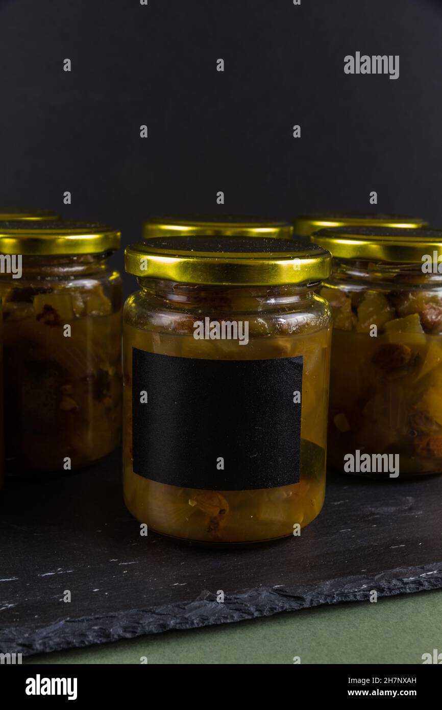 Chutney after courgette grew into marrow. Several jars black background ...