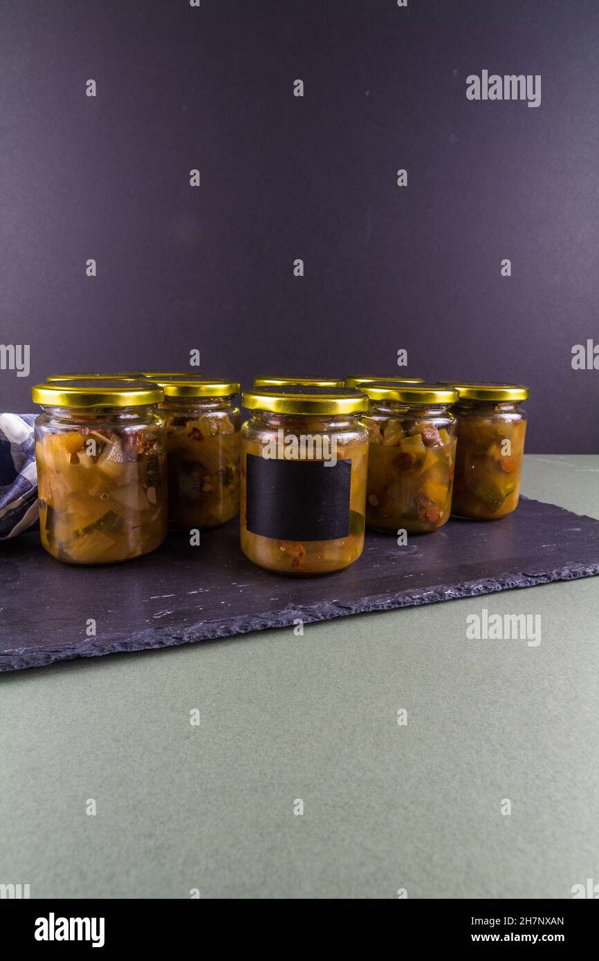 Chutney after courgette grew into marrow. Several jars black background ...
