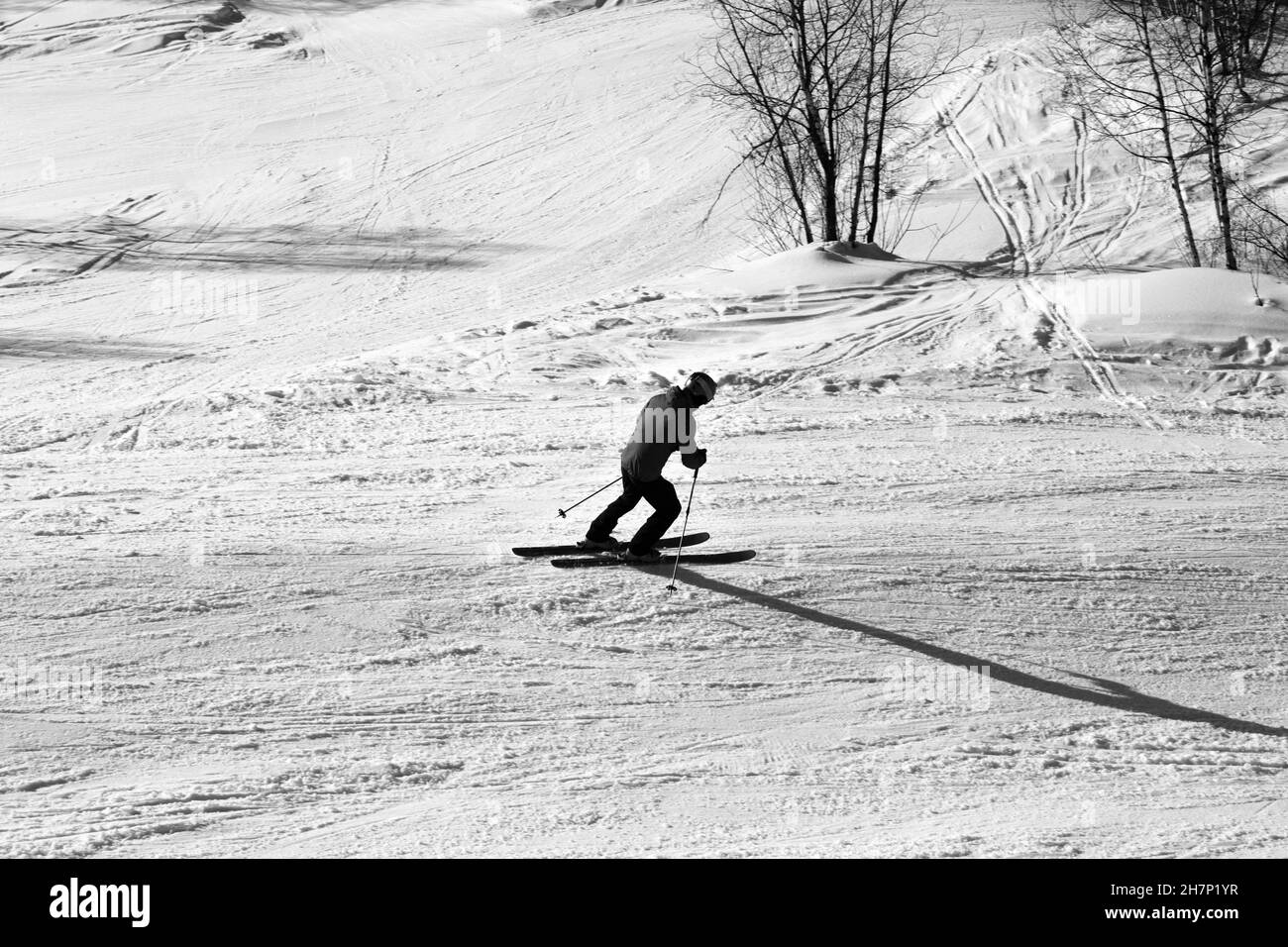 Skier downhill on snowy ski slope at winter day. Black and white toned ...