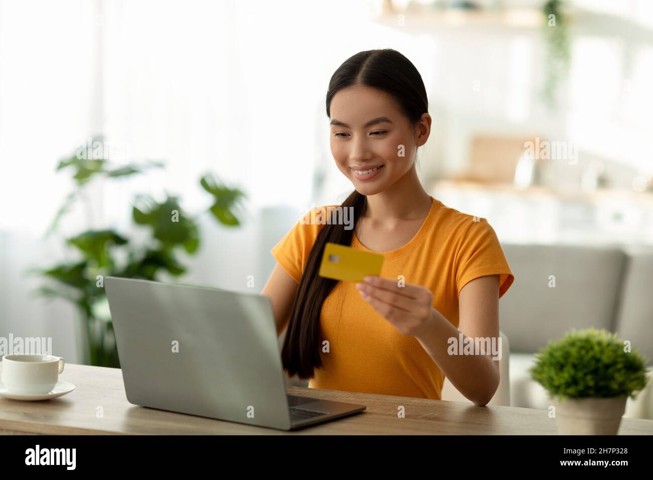 Positive asian lady shopping online, using credit card and laptop ...
