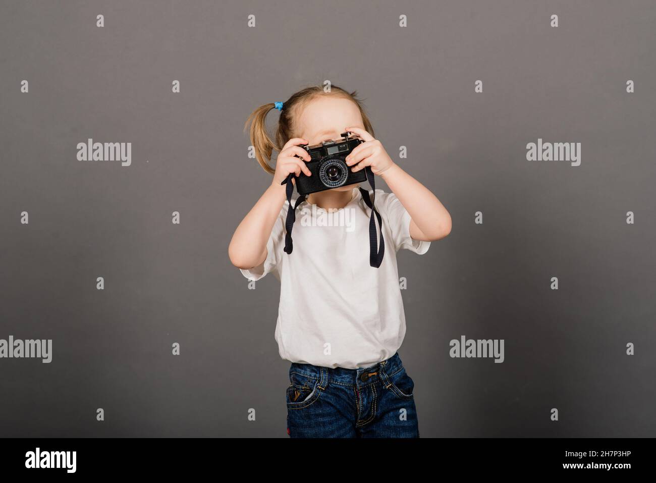 Child with camera. Little girl photographing in a studio background ...