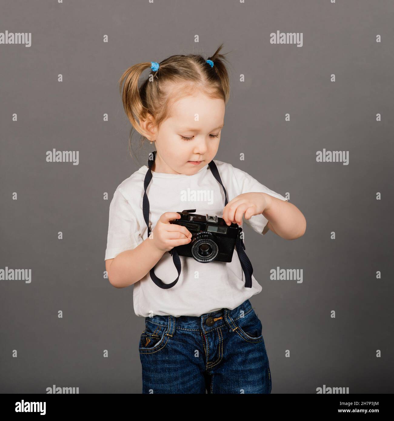 Child with camera. Little girl photographing in a studio background ...