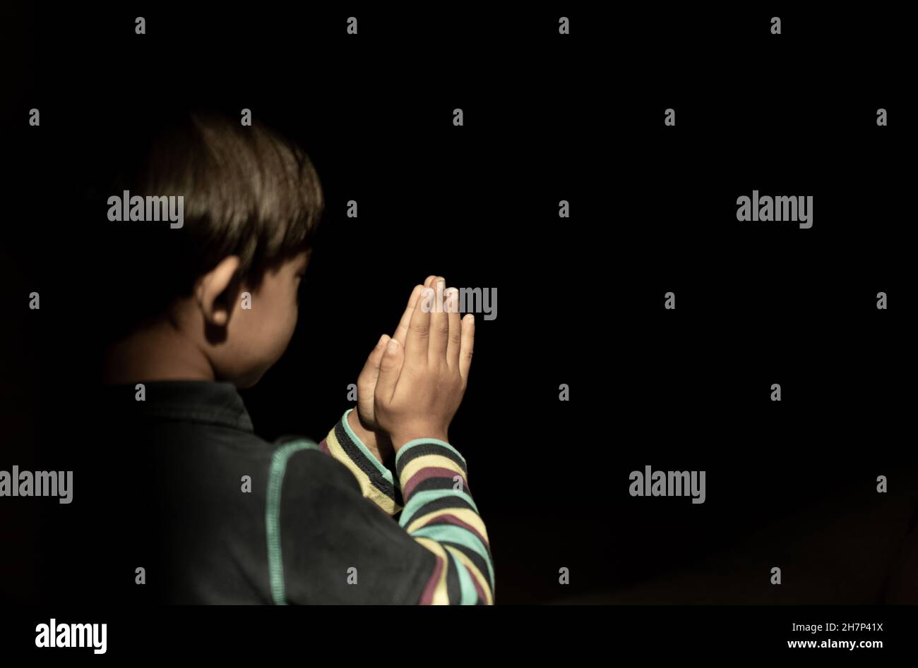 Little boy praying to God in dark background Stock Photo - Alamy