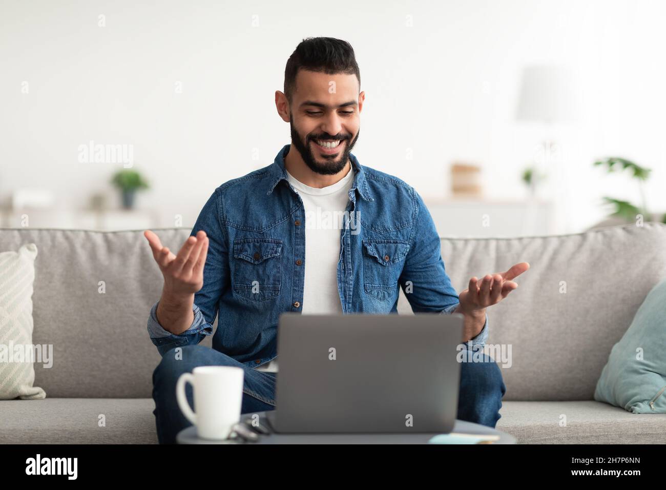 Young Arab guy having video call on laptop computer from home office ...