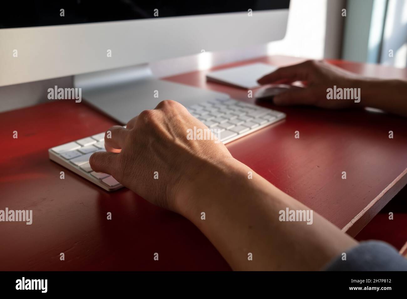 Woman works with a computer, one hand is on the keyboard, the other on ...