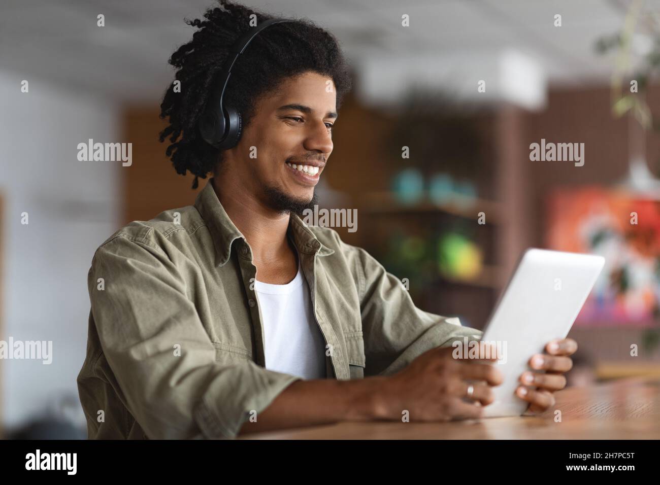 Happy Black Guy Wearing Wireless Headphones Using Digital Tablet At ...