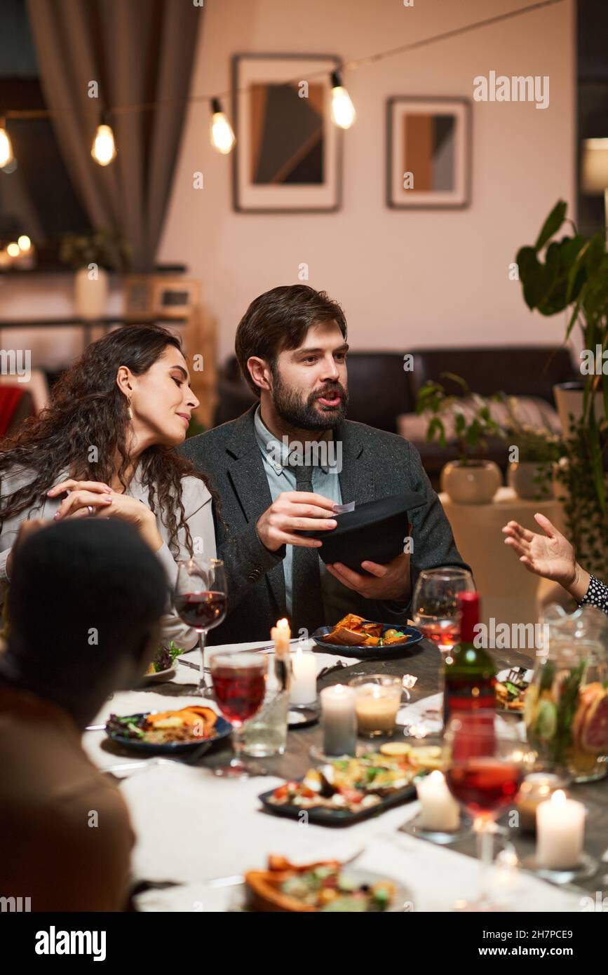 Young people sitting at festive dining table and talking, they having ...