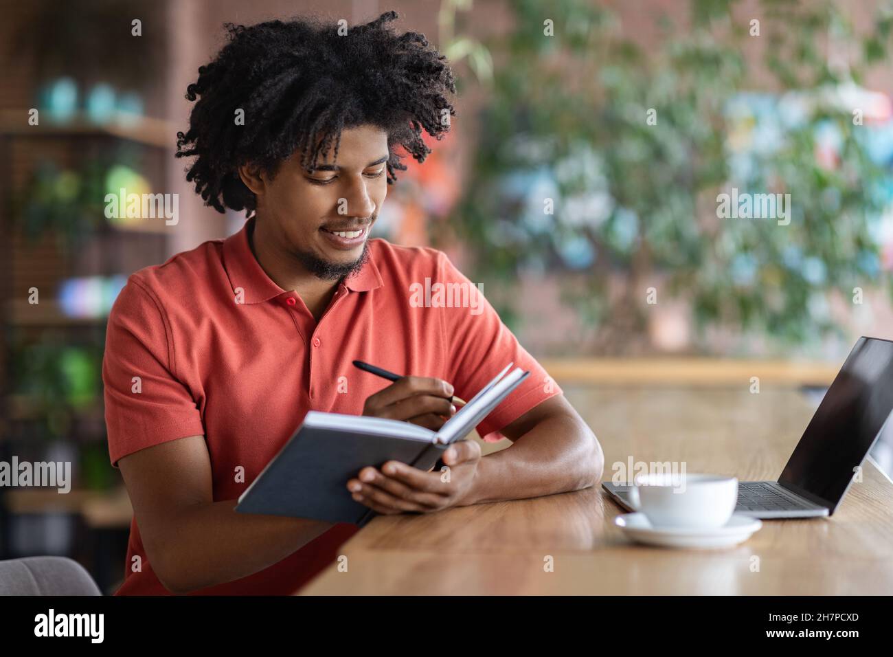 Time Management. Young Black Man Writing In Notepad While Sitting In ...