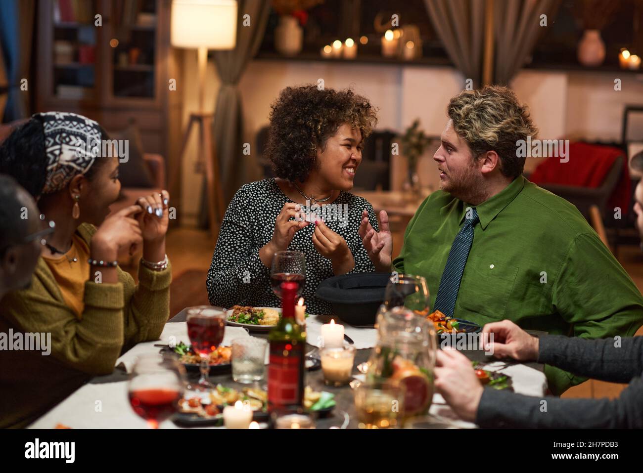 Group of friends having fun while sitting at dining table during dinner ...