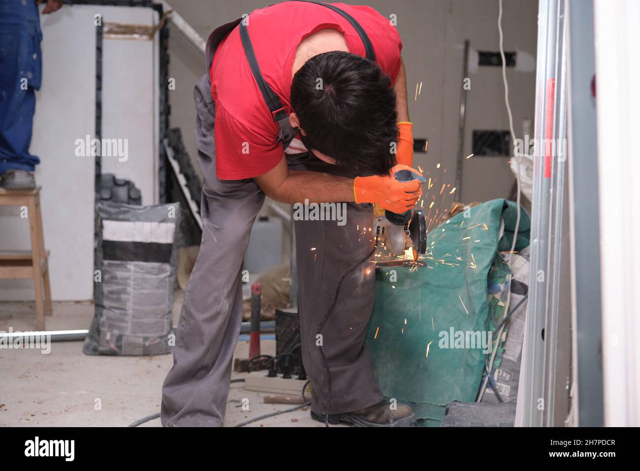 Worker cutting the metal frame to assemble a suspended ceiling with ...