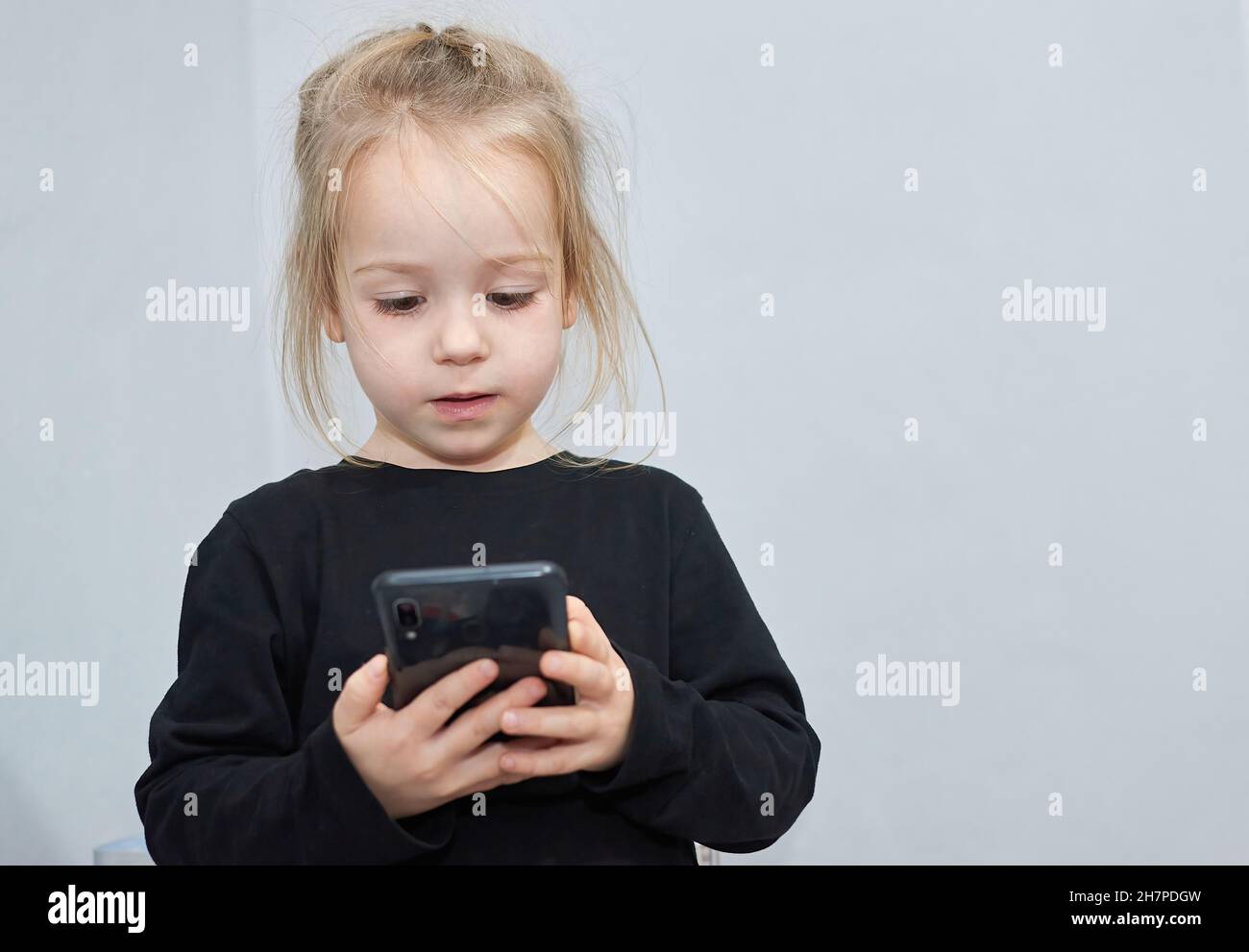 Surprised happy smiling little child girl toddler using mobile phone ...