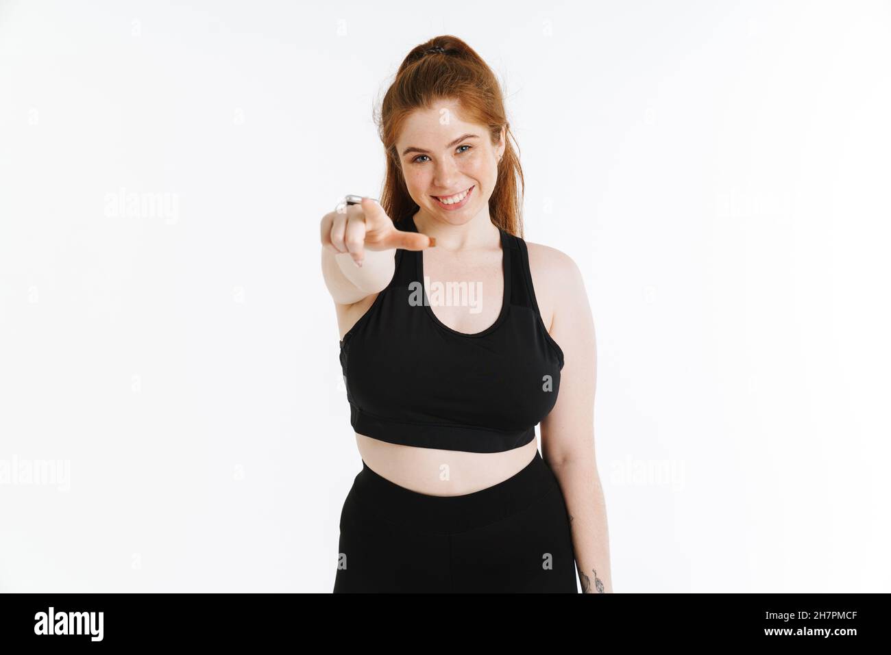 Young ginger woman smiling while pointing finger at camera isolated ...