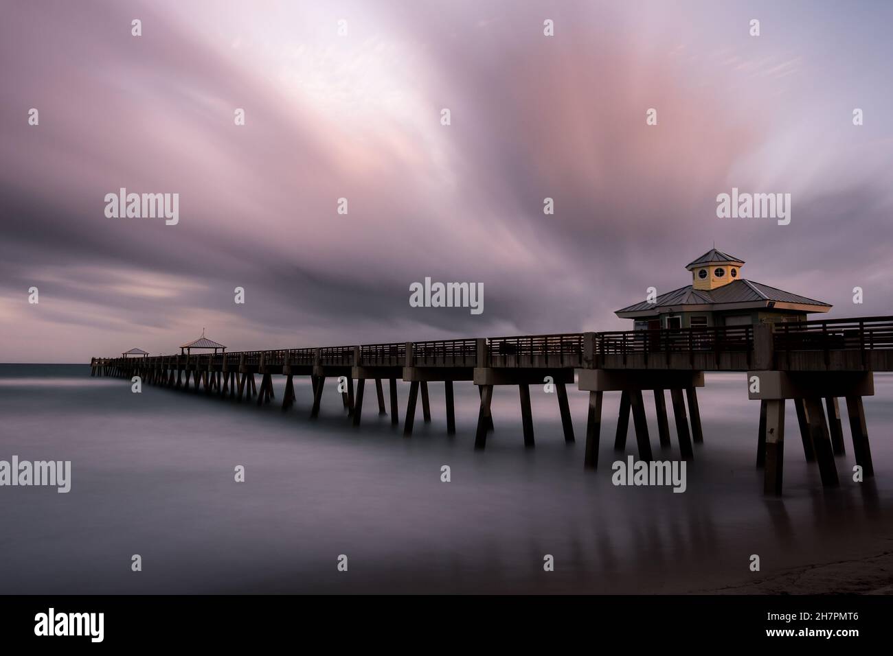 Mesmerizing view of a pier over the sea under a dramatic sunset sky ...
