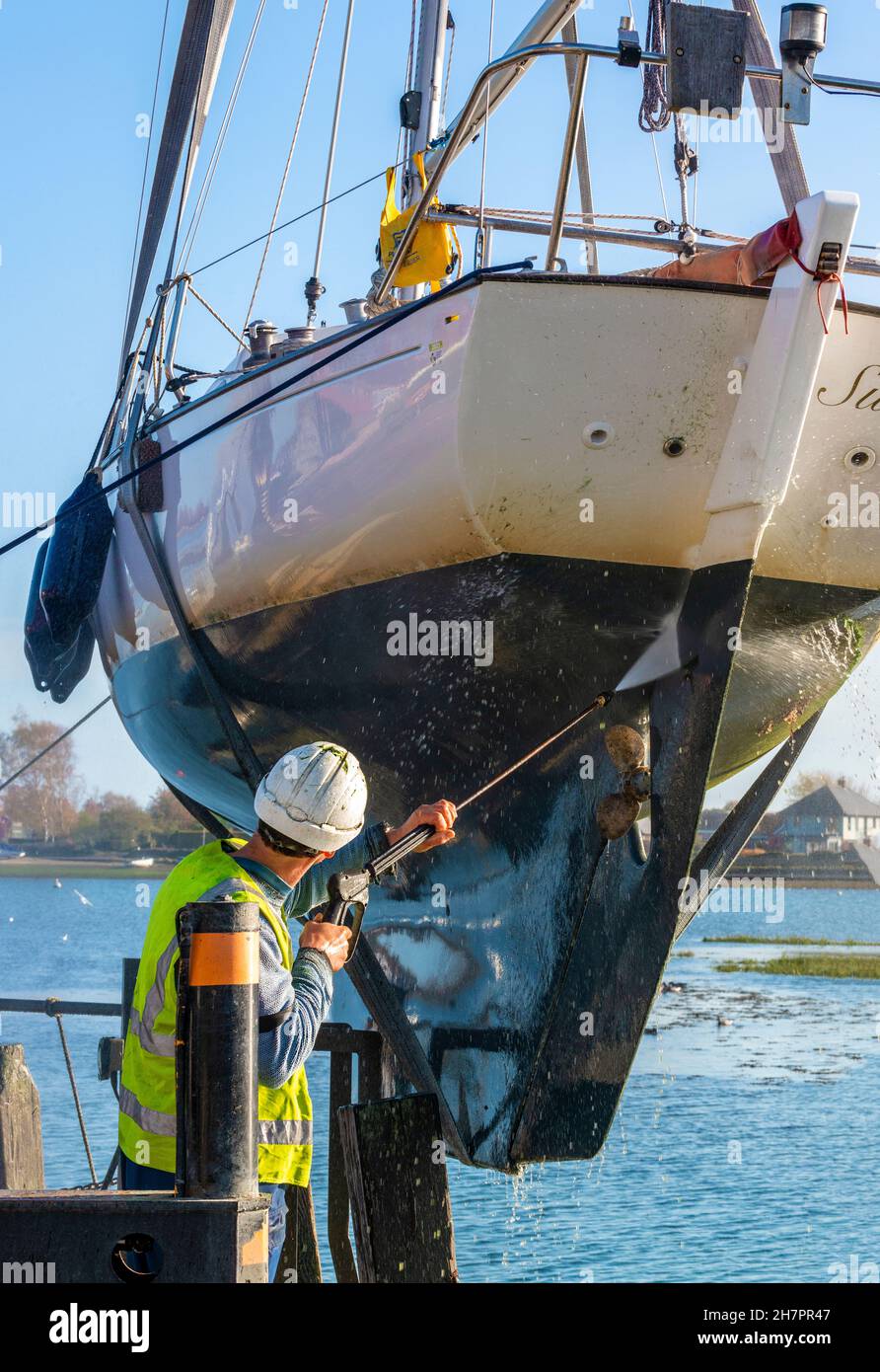 Yacht (Contessa 26)in crane slings at Bosham Quay being jet washed to ...