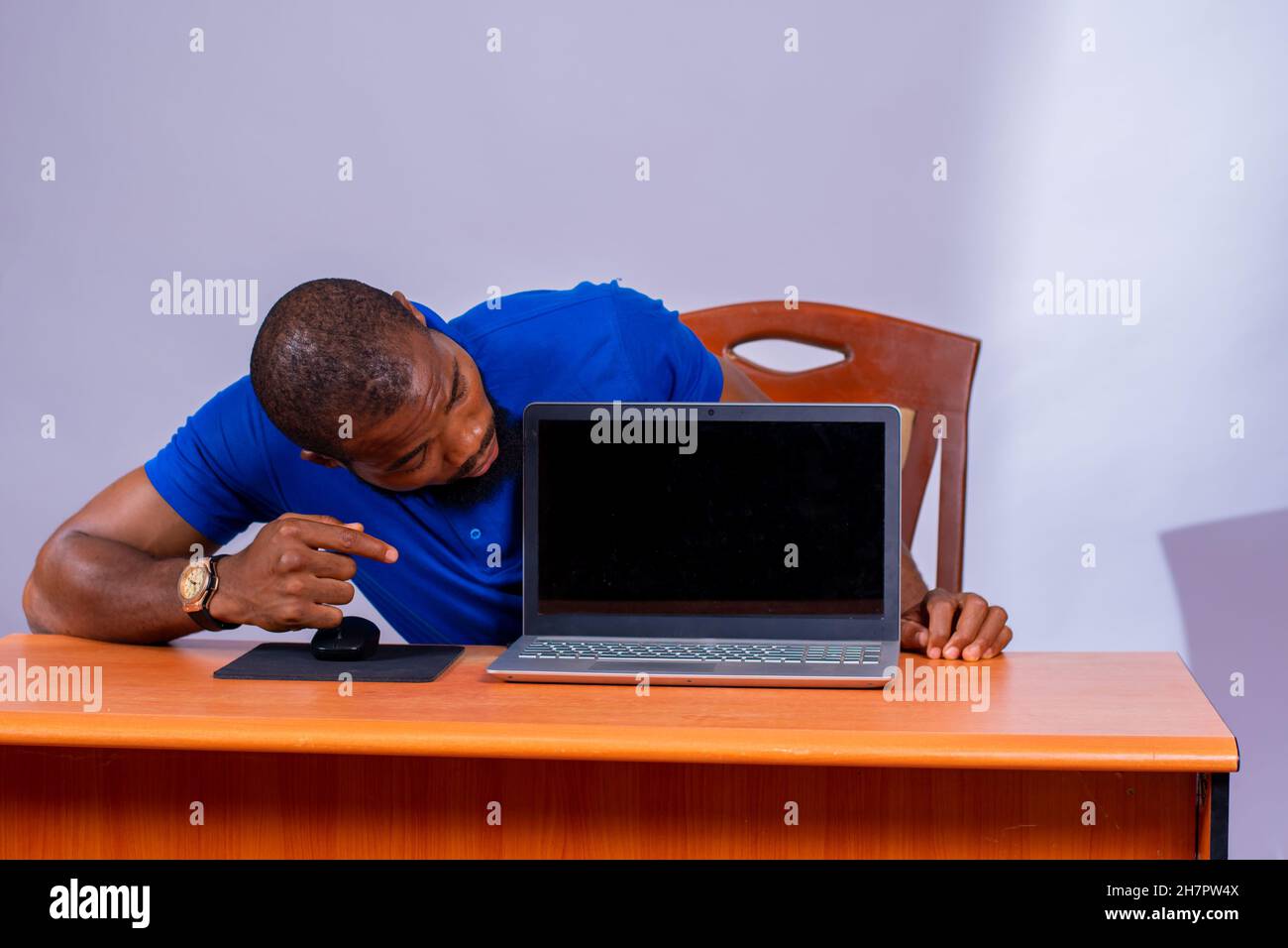 Young African male sitting at the office desk and showing his laptop ...