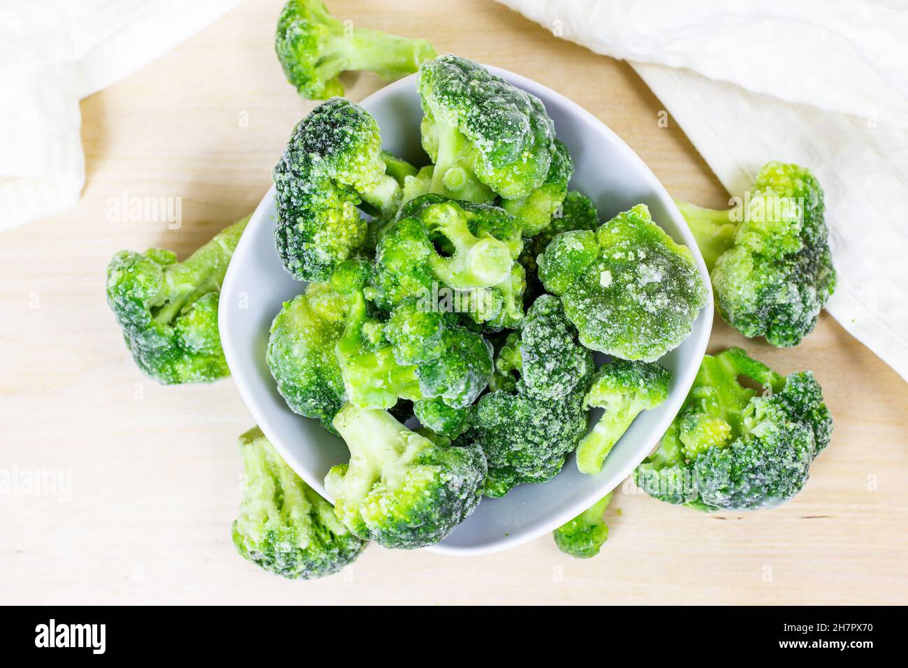 Top view of fresh green frozen broccoli in small white bowl on light ...