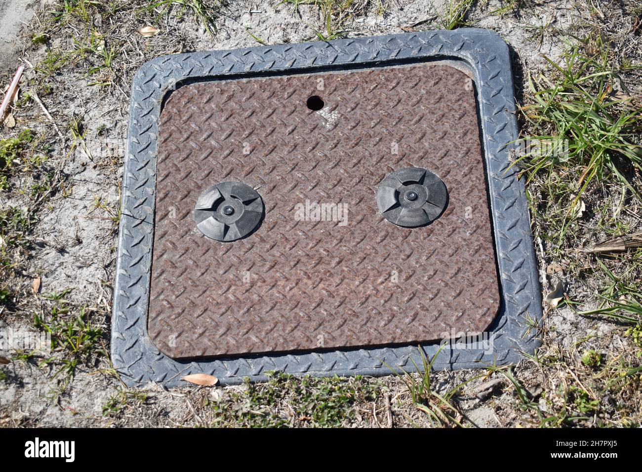 A metal lid covers access to underground pipes Stock Photo - Alamy