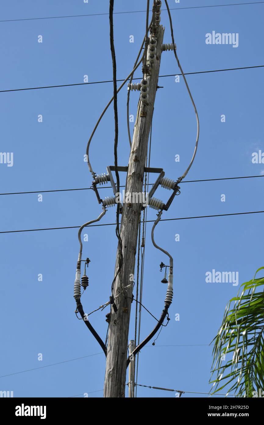 An old wooden utility pole bends with various electrical components ...