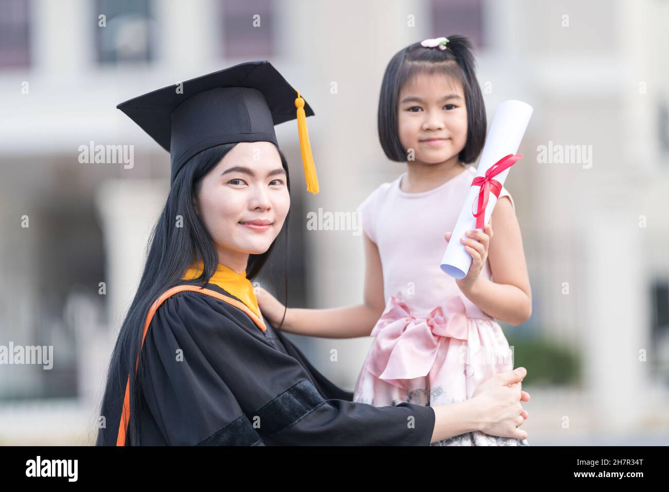 Southeast Asian woman graduate with a little girl on her graduation day ...