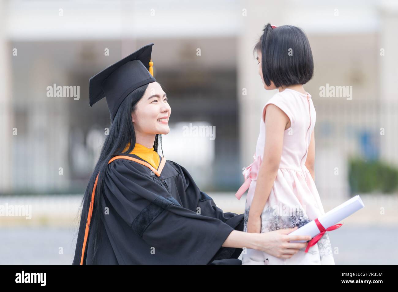 Southeast Asian woman graduate with a little girl on her graduation day ...