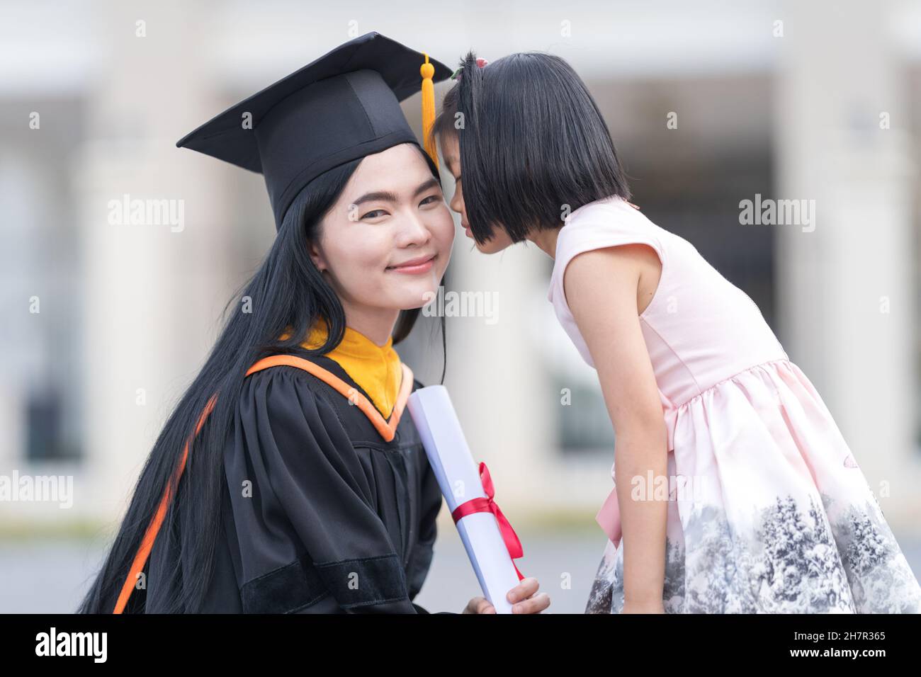 Southeast Asian woman graduate with a little girl on her graduation day ...