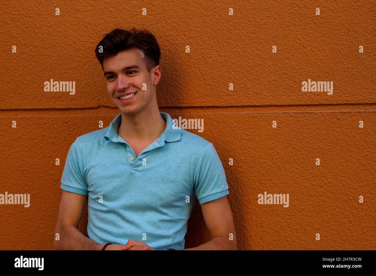 Handsome smiling Spanish male leaning on a wall Stock Photo - Alamy