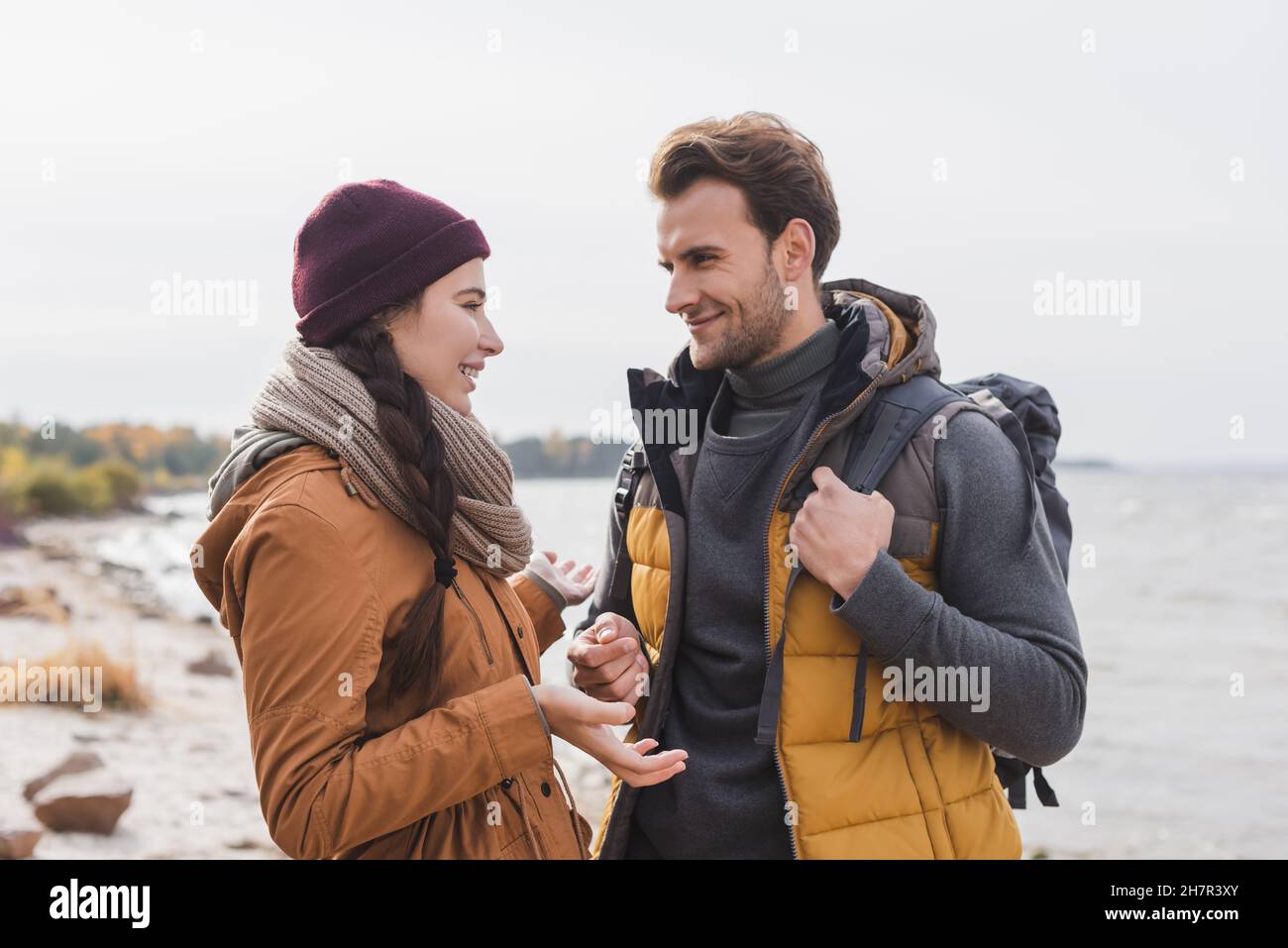 young woman gesturing while talking to smiling boyfriend while walking ...