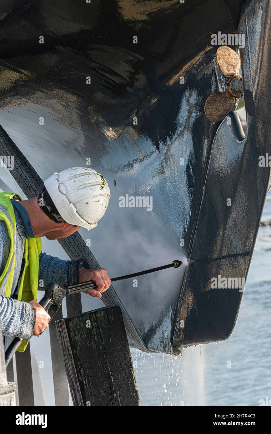 Yacht (Contessa 26)in crane slings at Bosham Quay being jet washed to ...