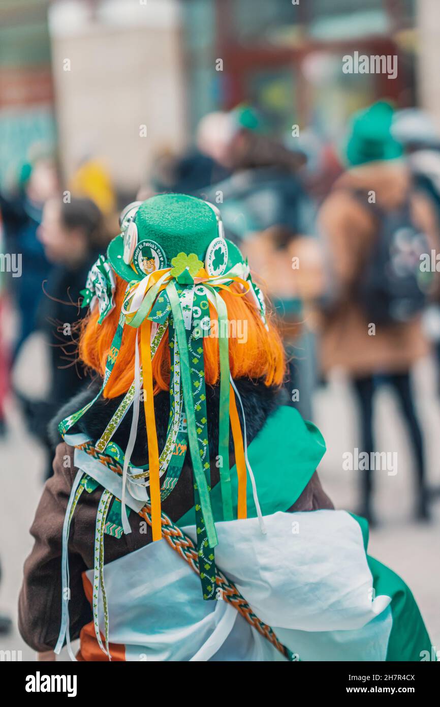 Girl in green festive hat with decor back to us, people in irish ...