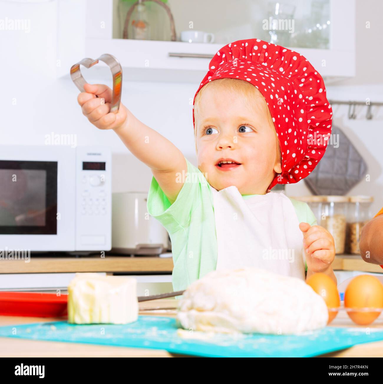 Boy in chef hat show heart form for cookie baking Stock Photo - Alamy