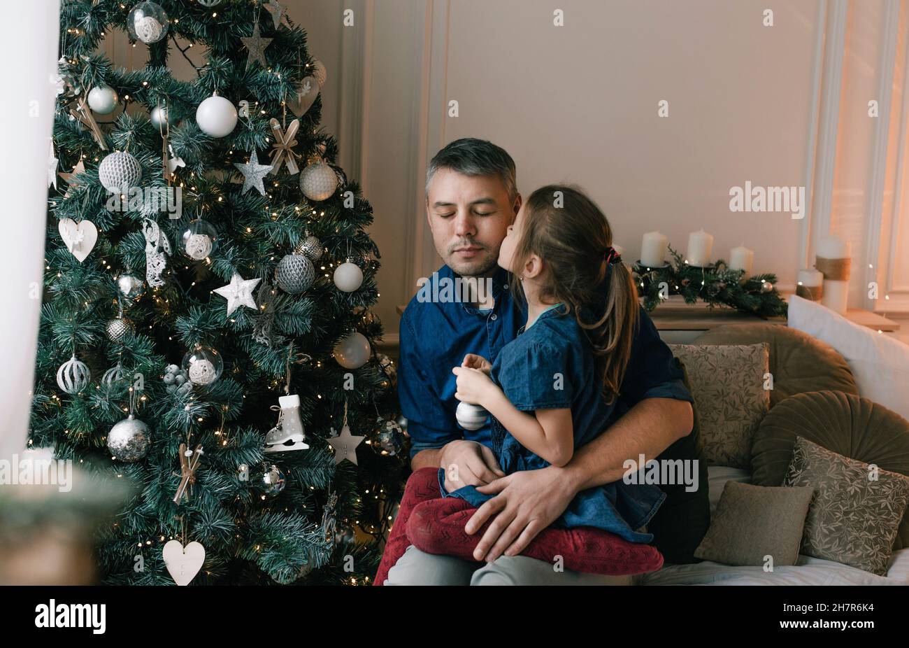 little daughter gently kisses dad on the cheek while decorating the ...