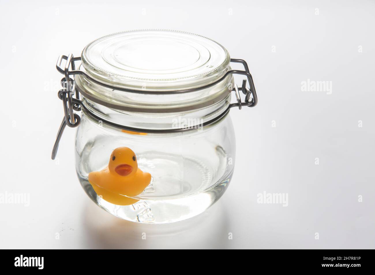 Small yellow rubber duck in a glass jar of water. Concept - restriction ...