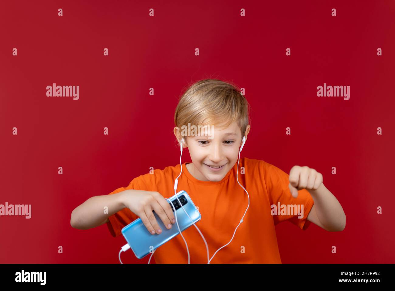 cheerful boy smiling and dancing while listening to music through ...