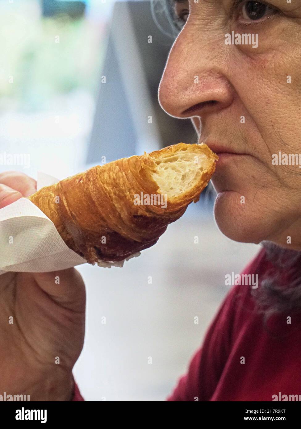 Old Hispanic woman eating a croissant in a cafe Stock Photo - Alamy
