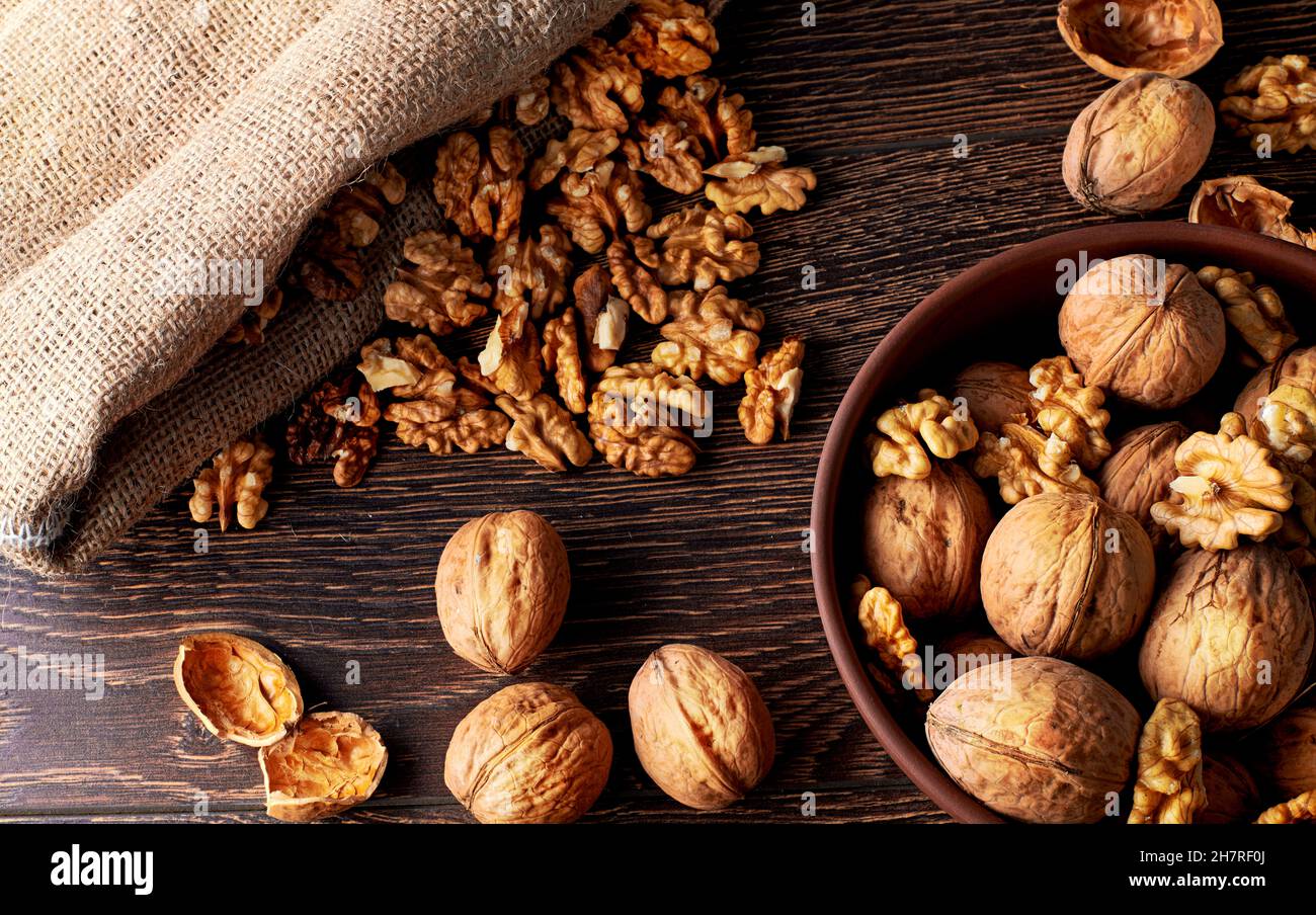 Walnut kernels and whole walnuts on a rustic old wooden table backlit ...