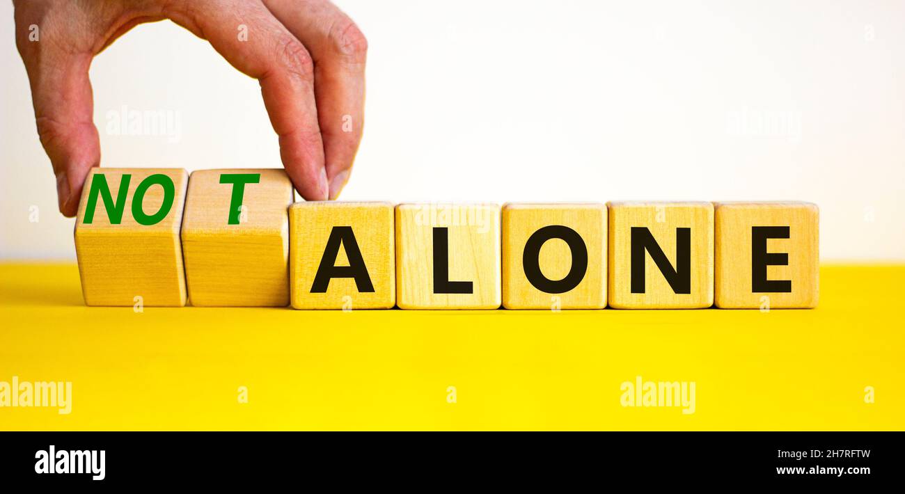 You are not alone symbol. Businessman turns wooden cubes and changes ...