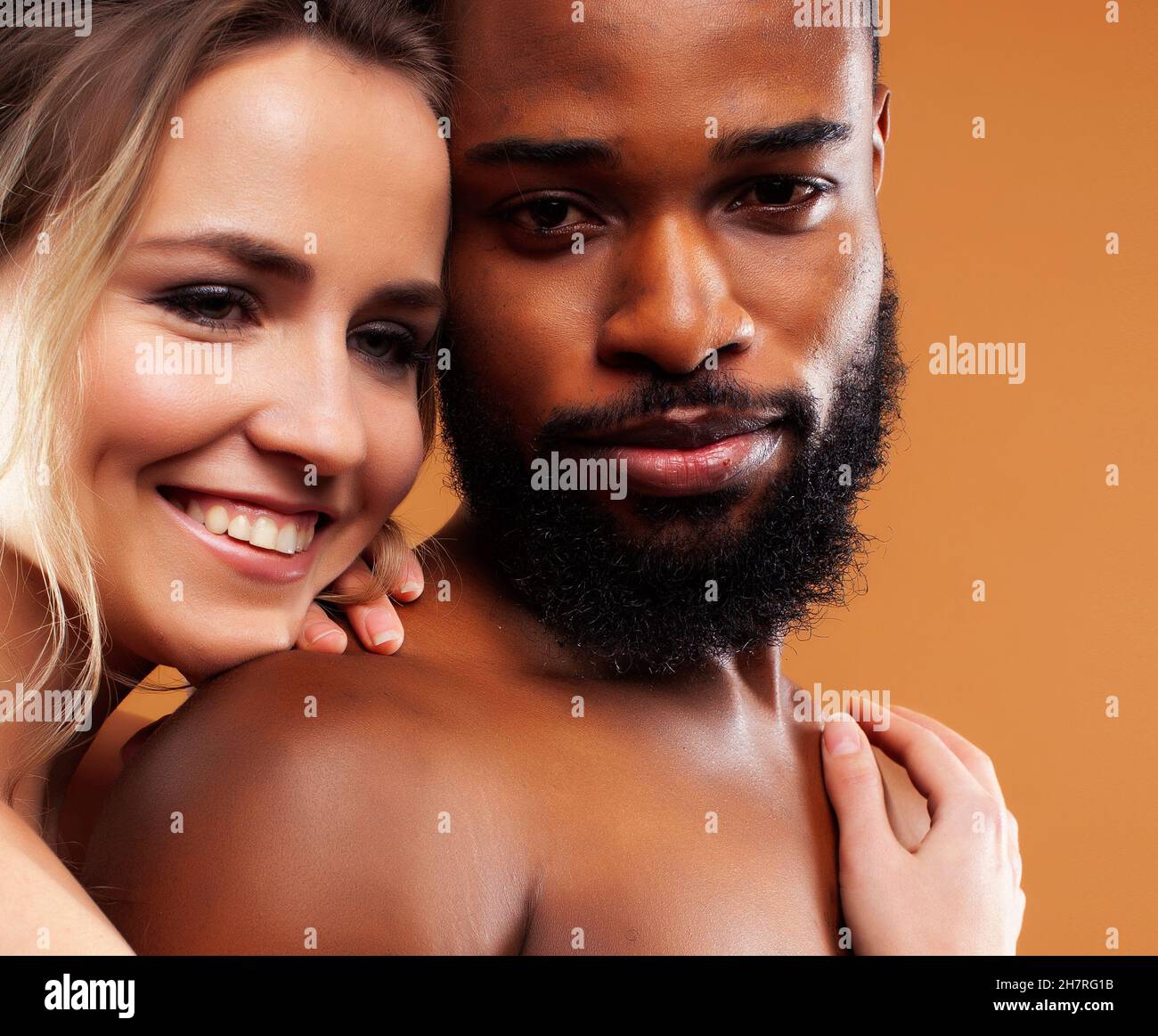 Young pretty couple diverse races together posing sensitive on brown ...